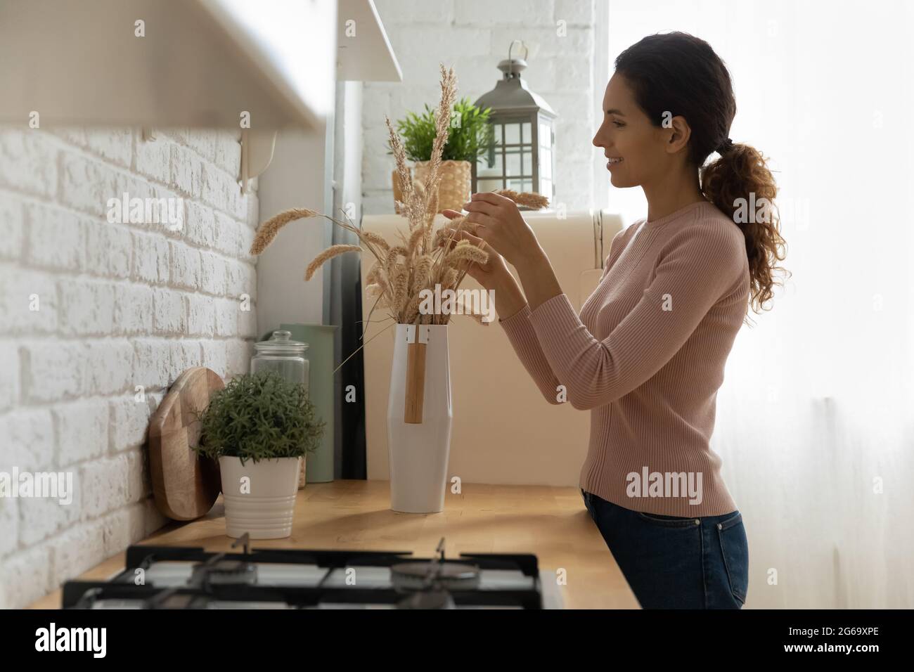 Smiling female homeowner improving dwelling with dried flowers Stock ...