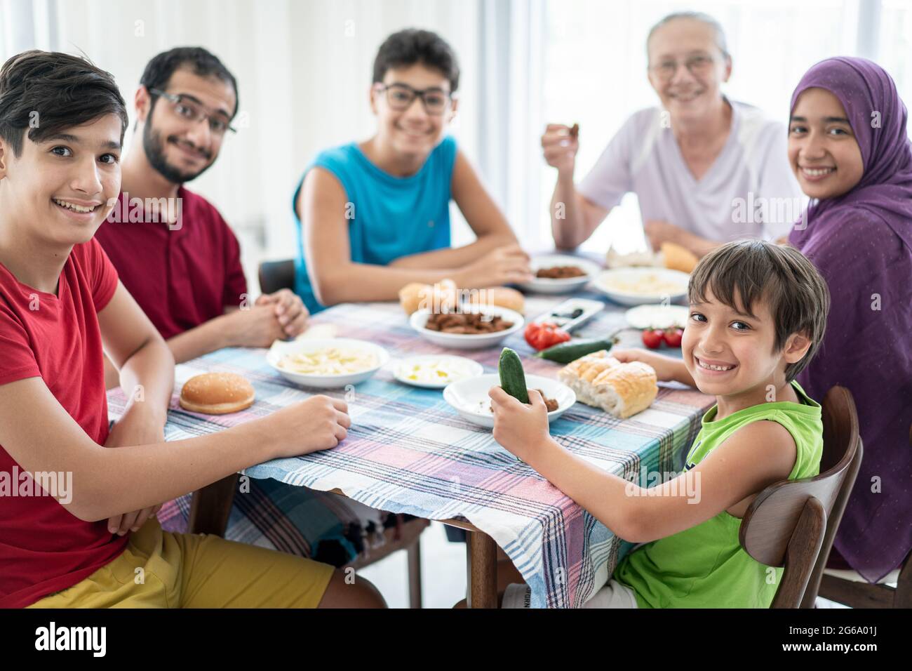 Happy family enjoying eating food in dining room Stock Photo - Alamy