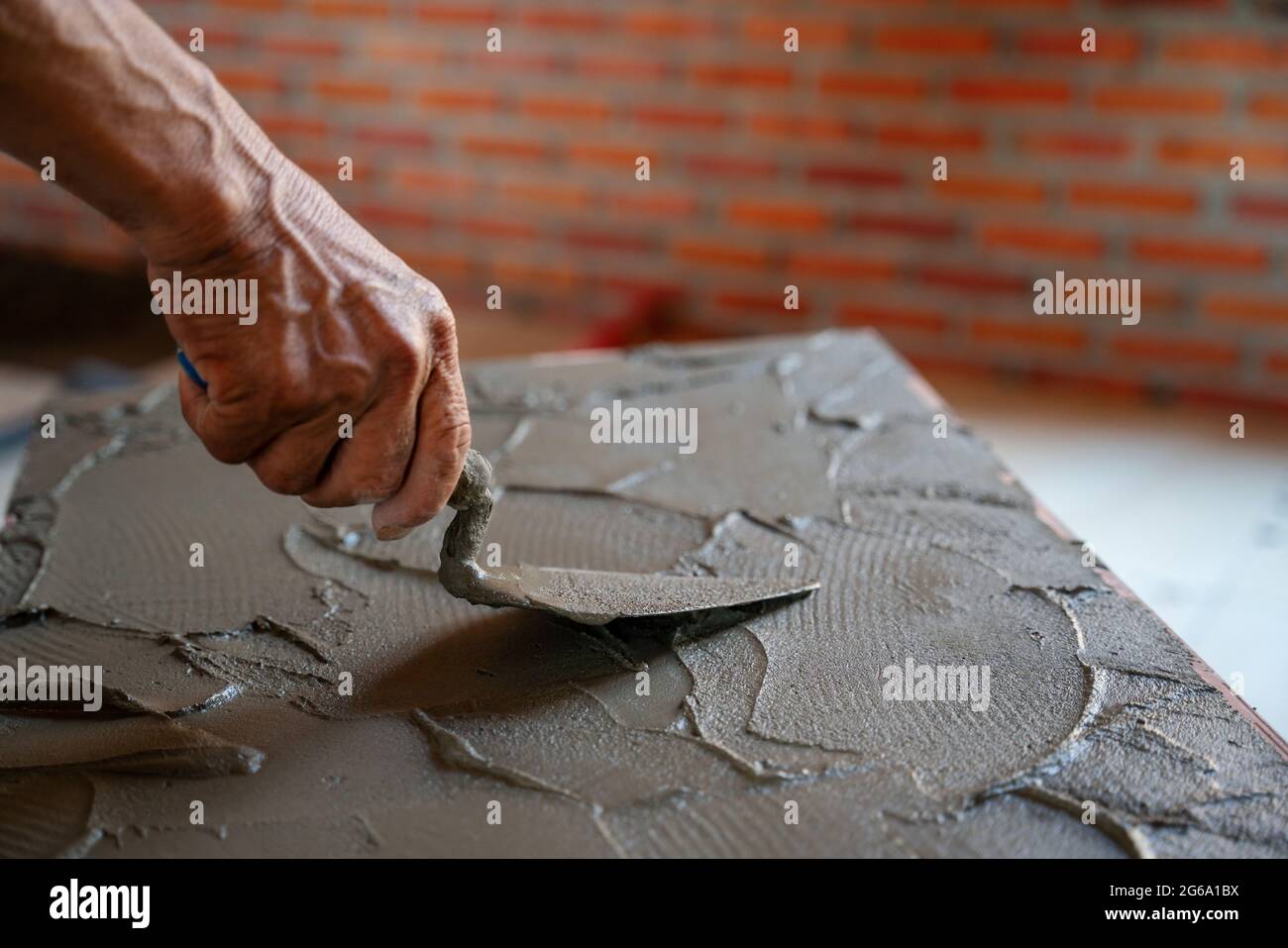 closeup hand of tilers use trowel adhesive mortar for floor tiles for ...