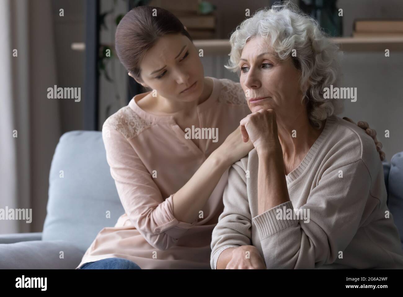 Young female caregiver support grieving suffering mature old woman ...