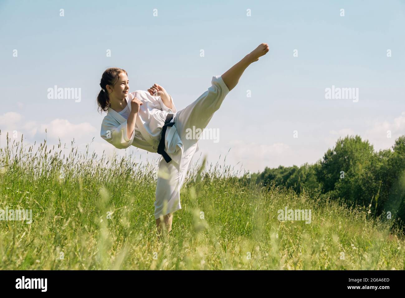 teen girl practicing karate kata outdoors, performs the mawashi geri ...