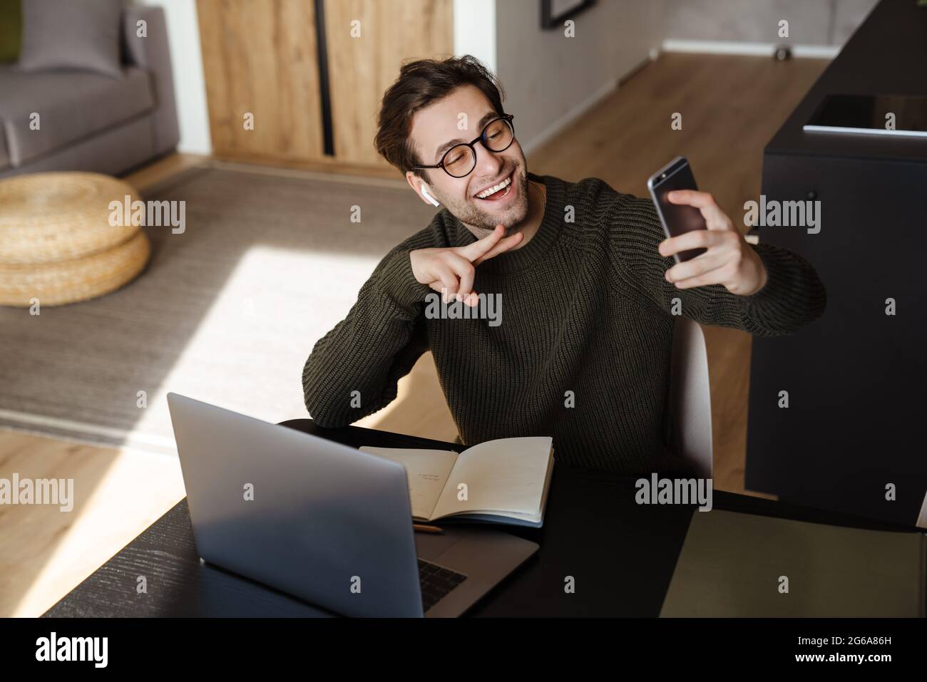 Smiling mid aged man working on laptop computer from home, taking a ...