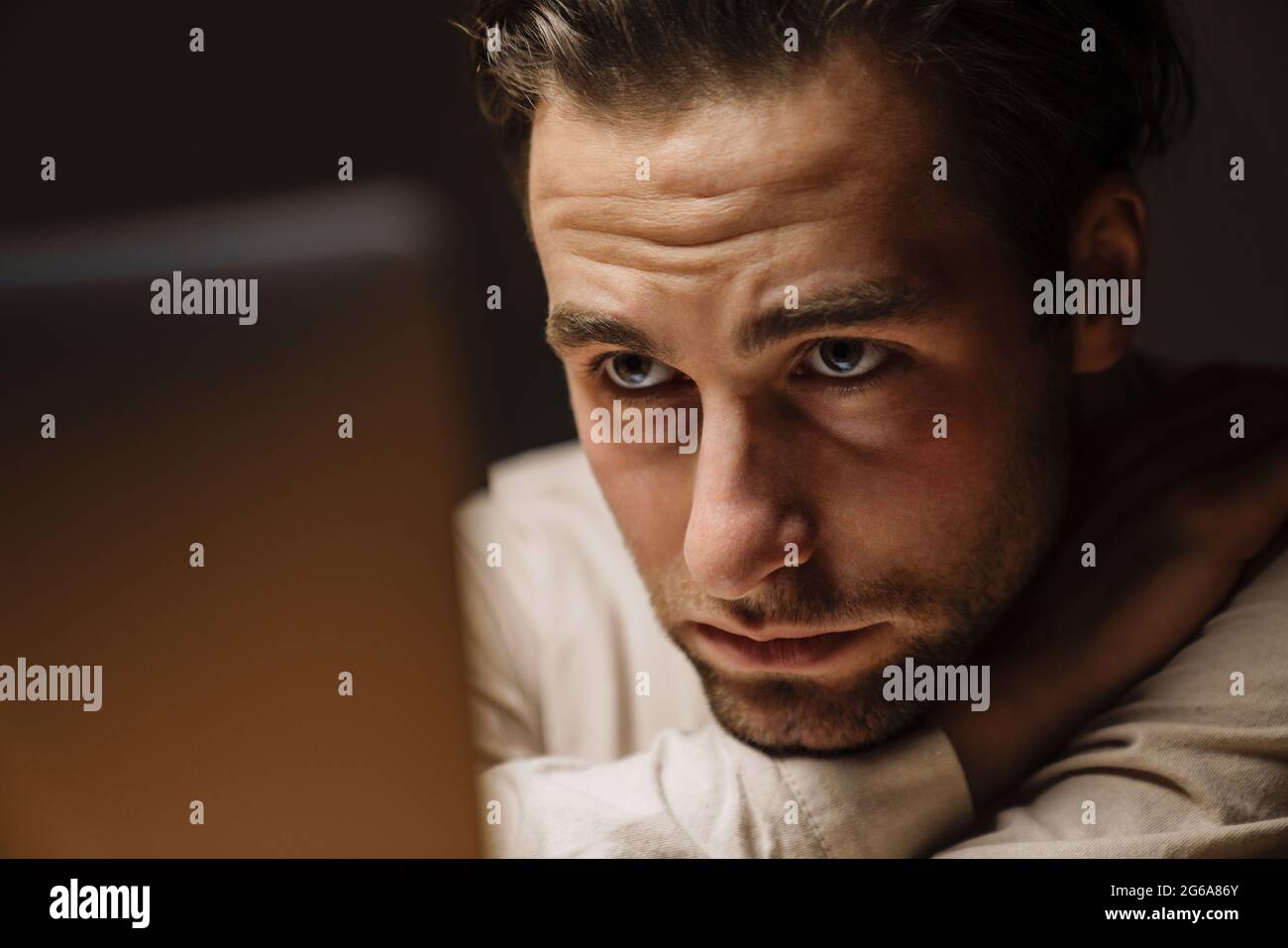 Tired bored mid aged brunette man looking at laptop screen while ...