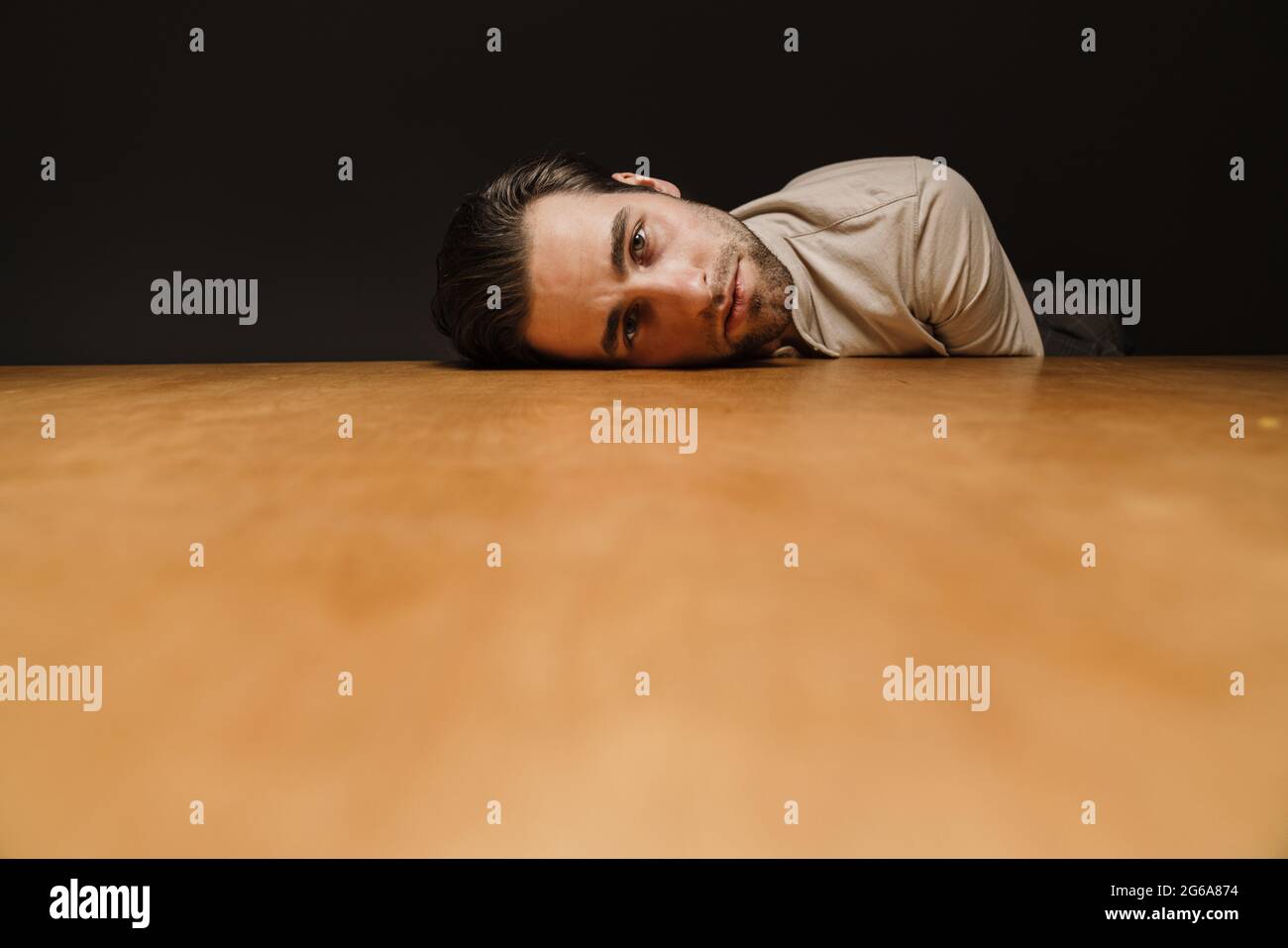 Upset sad man laying his head on a table indoors, looking at camera ...