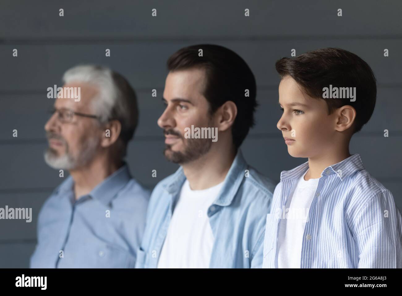 Serious boy, his father and grandpa standing together in row Stock ...