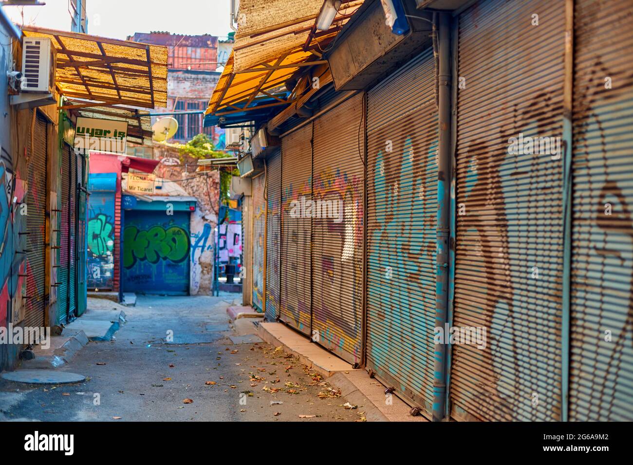 Narrow market street covered with graffiti. The roller shutters of the ...