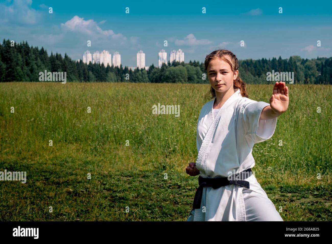 teen girl practicing karate kata outdoors, performing a strike oi zuki ...