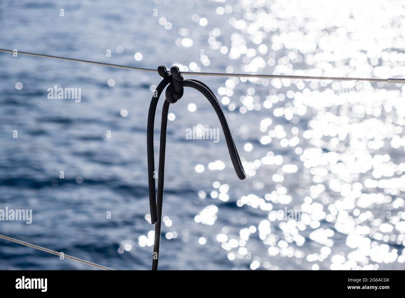 Boat railing detail. Black rope tied knot on stainless steel wire cable ...