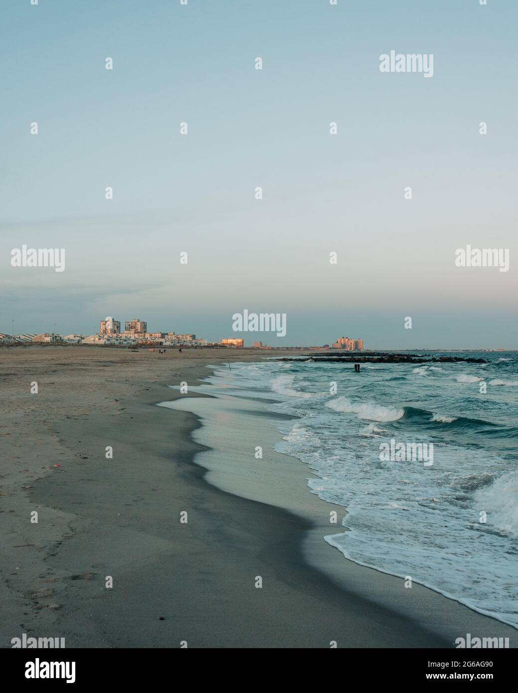 A beach with waves and buildings in the distance, Rockaways, Queens, New York City Stock Photo ...