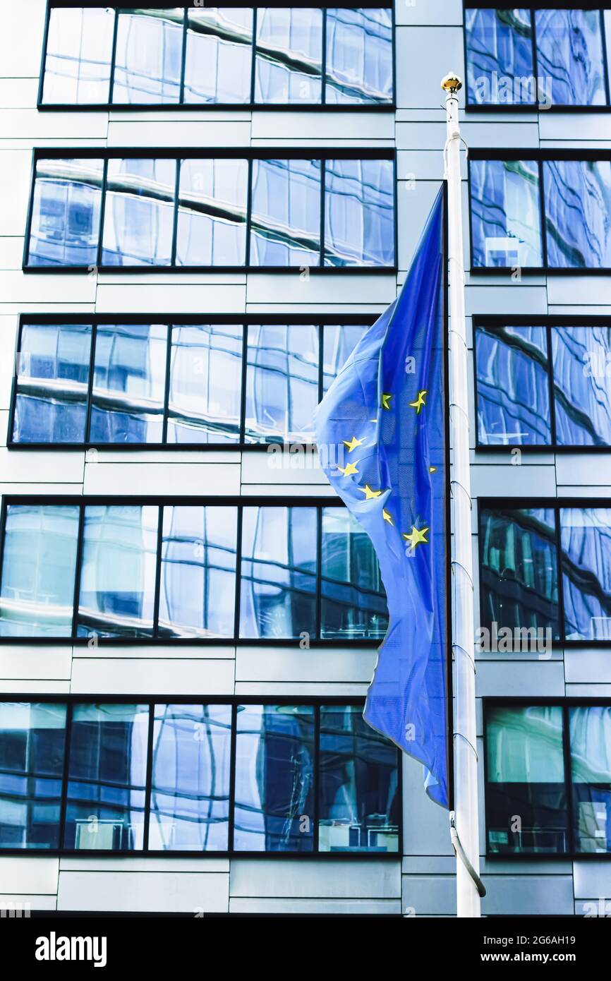 European Union flag waving in front of modern corporate office building ...