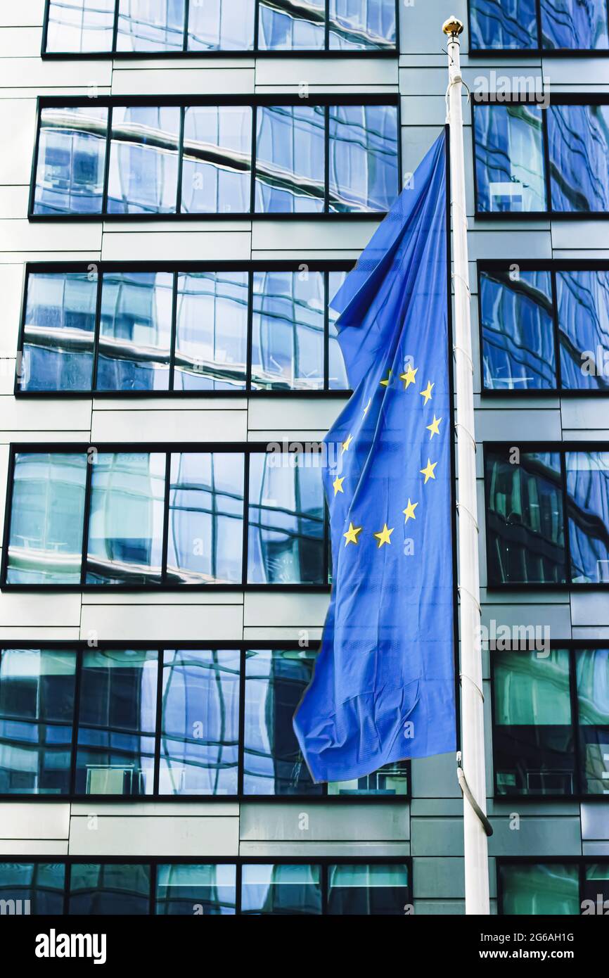 European Union flag waving in front of modern corporate office building ...