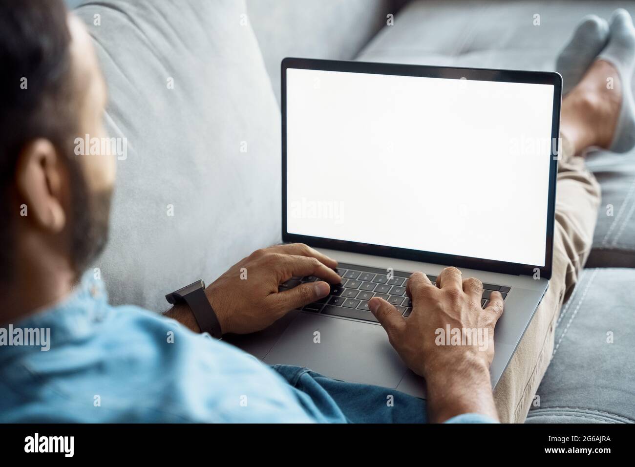 Rear view on white blank screen over shoulder man typing on laptop ...