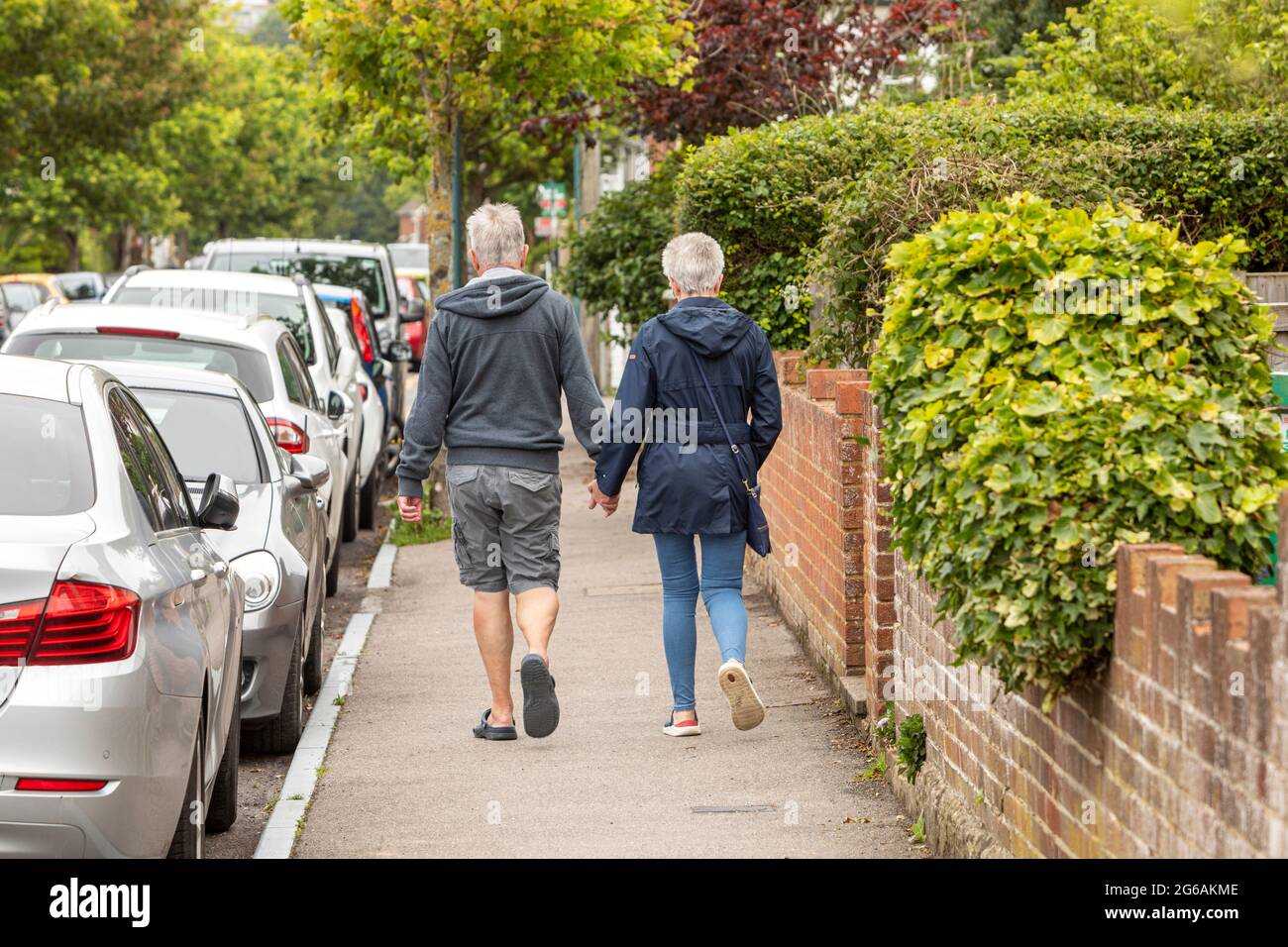 A middle aged couple walking hand in hand on an urban footpath Stock ...