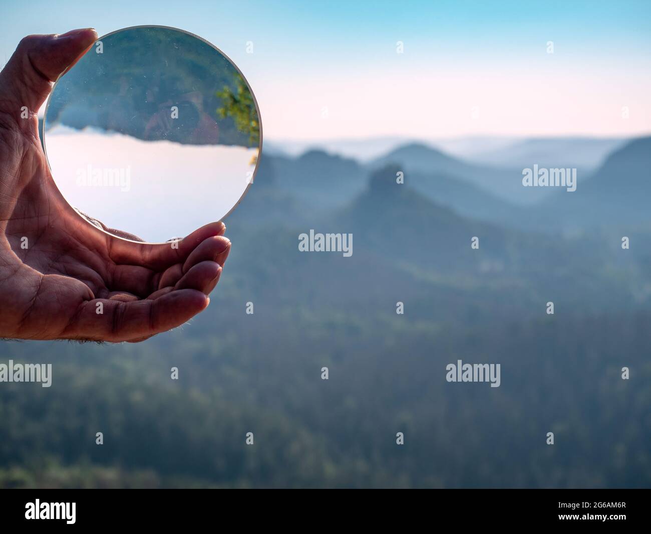 Sunset over valley with sharp hills captured in glass ball, reflection ...