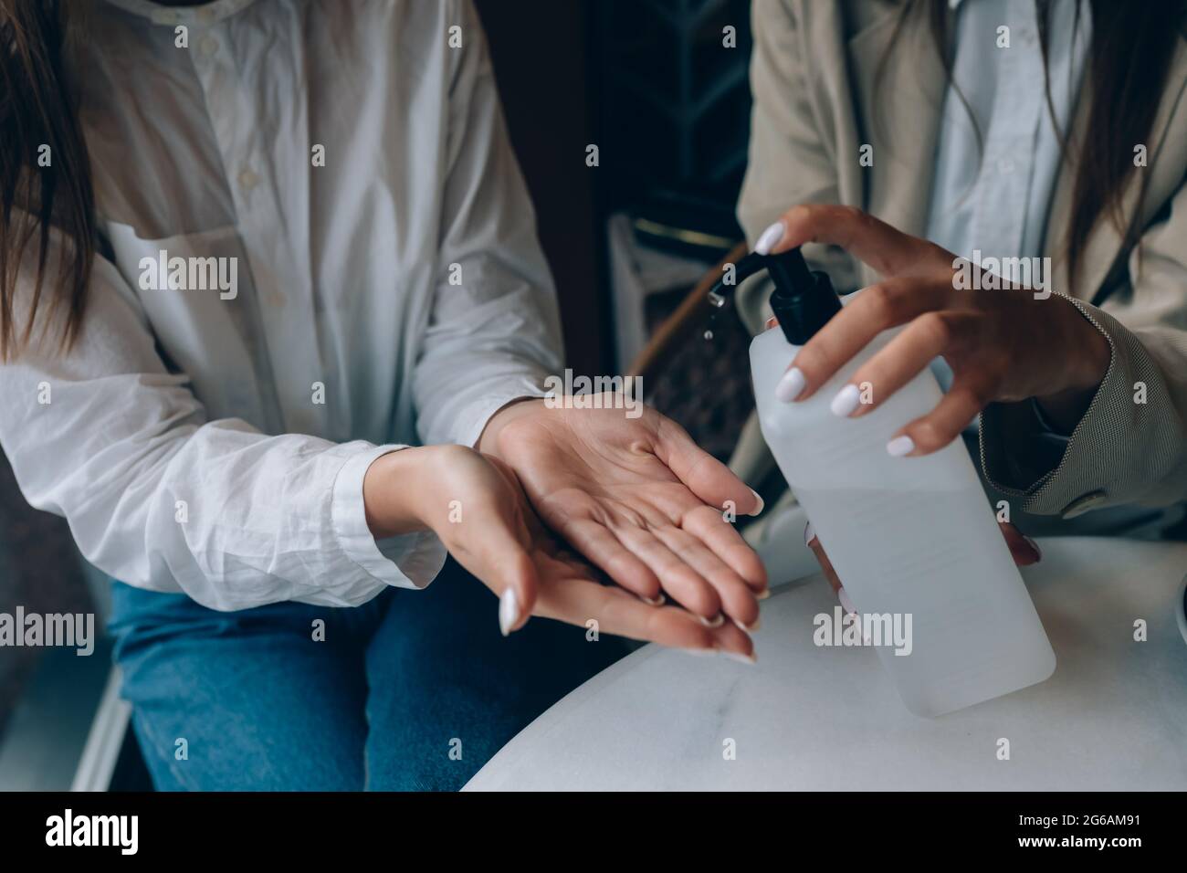 Women using an antibacterial antiseptic to disinfect at cafe Stock ...