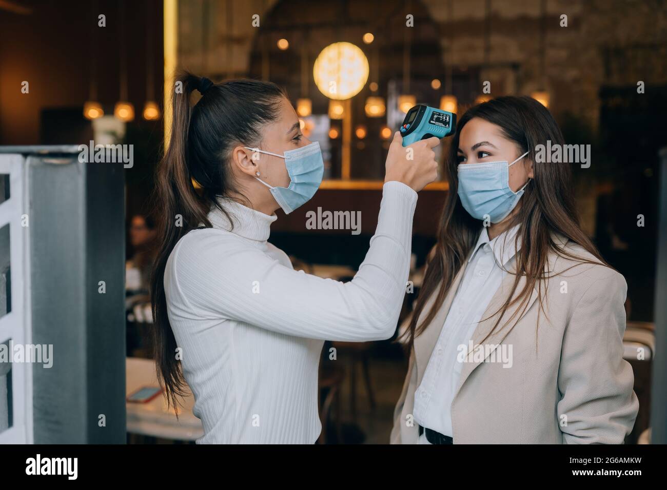 Woman measuring body temperature with contactless body thermometer ...