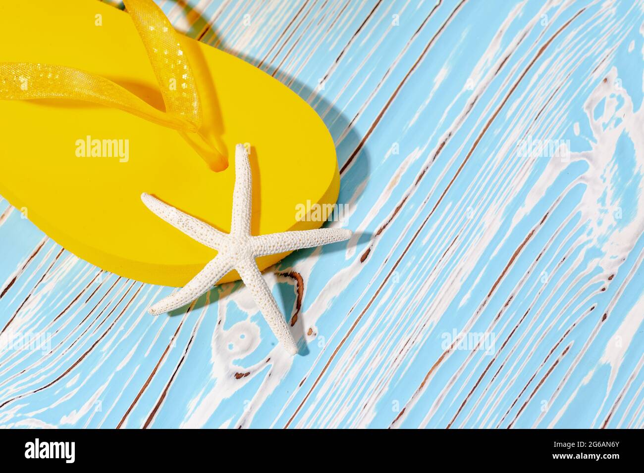 yellow rubber beach flip flops and starfish on a blue wooden background ...