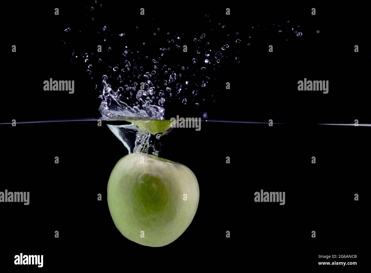 Ripe green apple falling down into clear water with splashes against ...