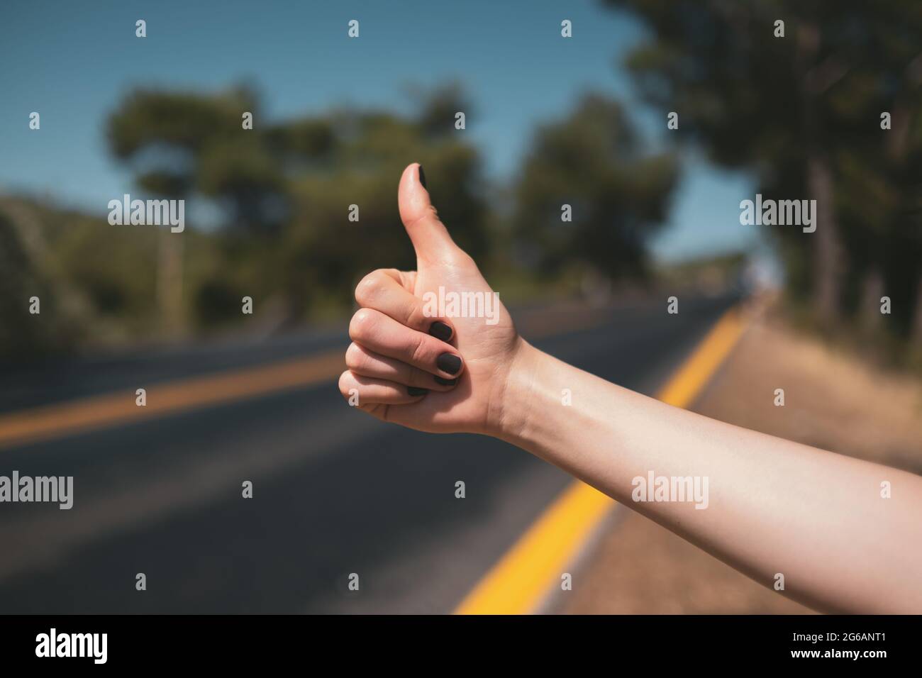 Close up shot of a womans hand doing hitchhiking sign near the country ...