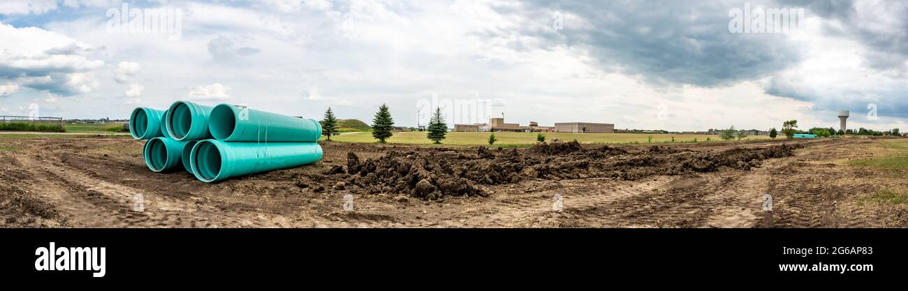 Stacked water main pipe with bell fitting next to an exposed trench for ...