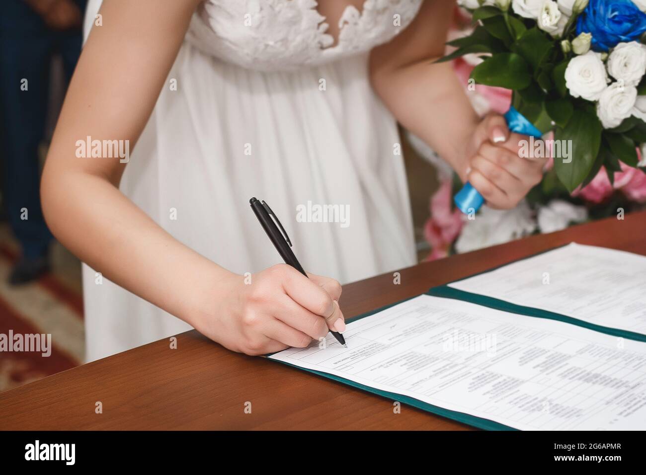 The hand of a young girl bride at the wedding puts the signature of ...