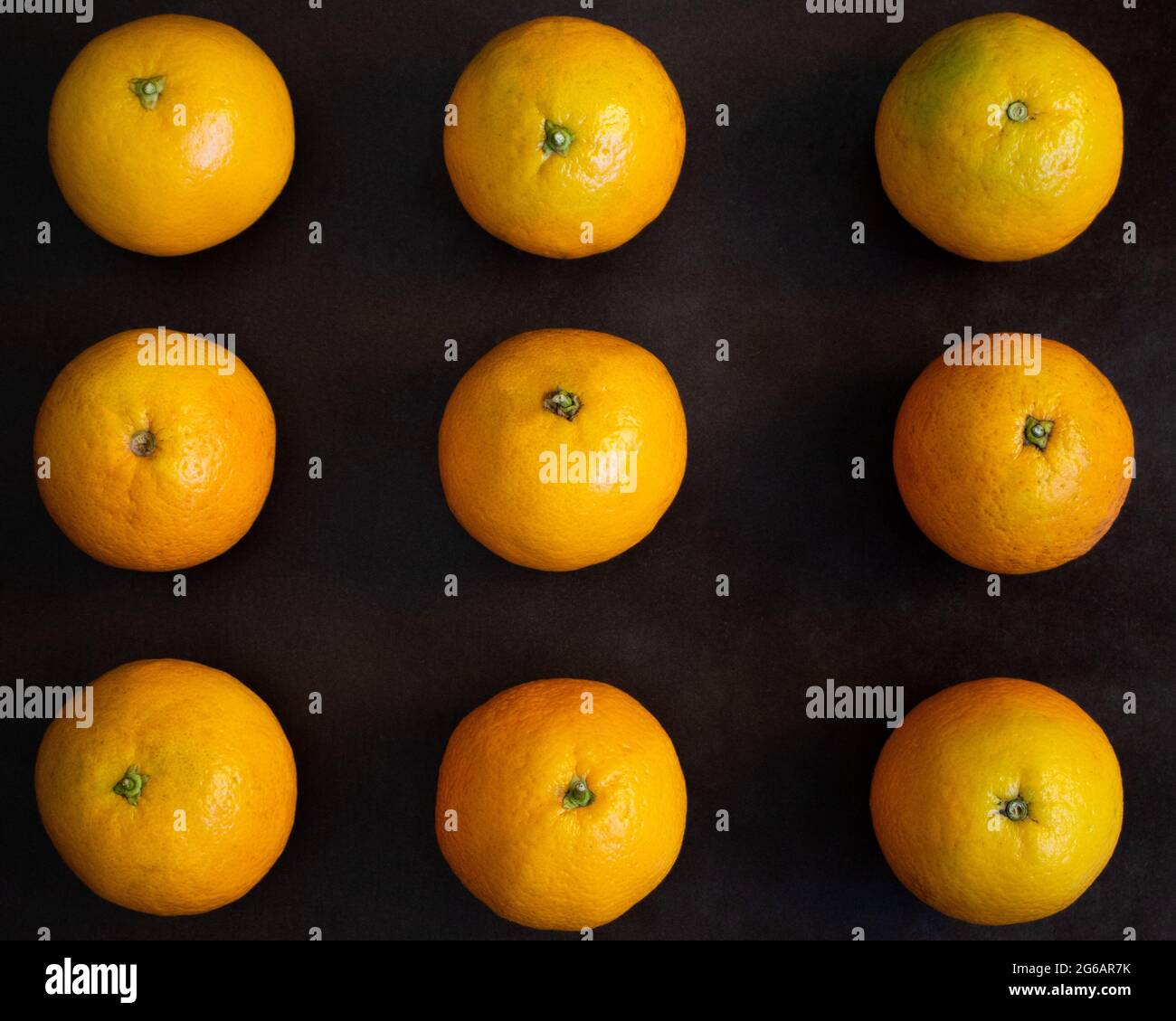 Three rows of oranges lined up on a dark counter. Top down view flat ...