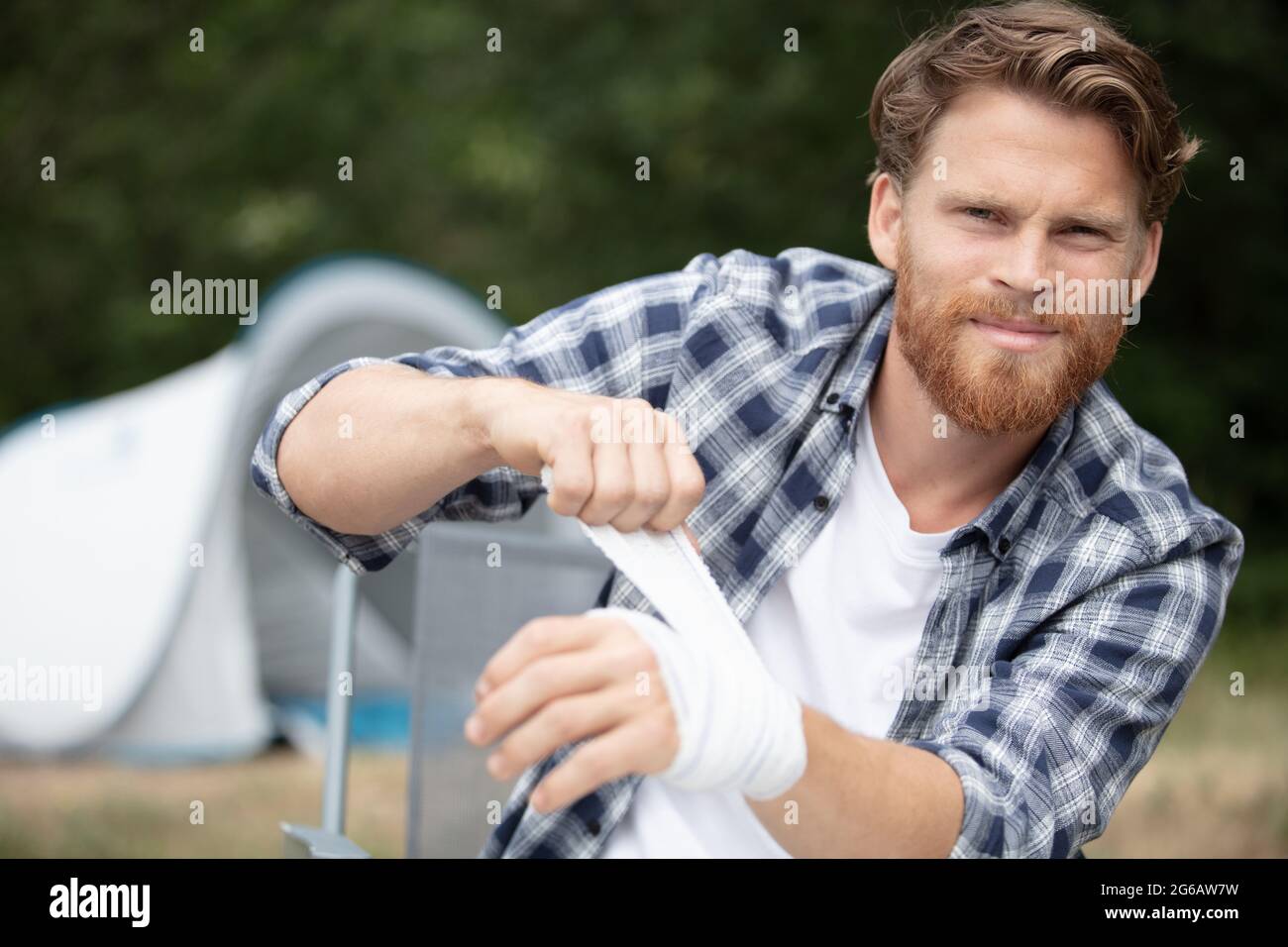 man bandaging arm during camping holiday Stock Photo - Alamy