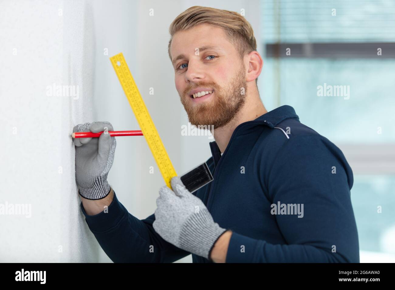man in denim is using ruler for fixing photo frame Stock Photo - Alamy