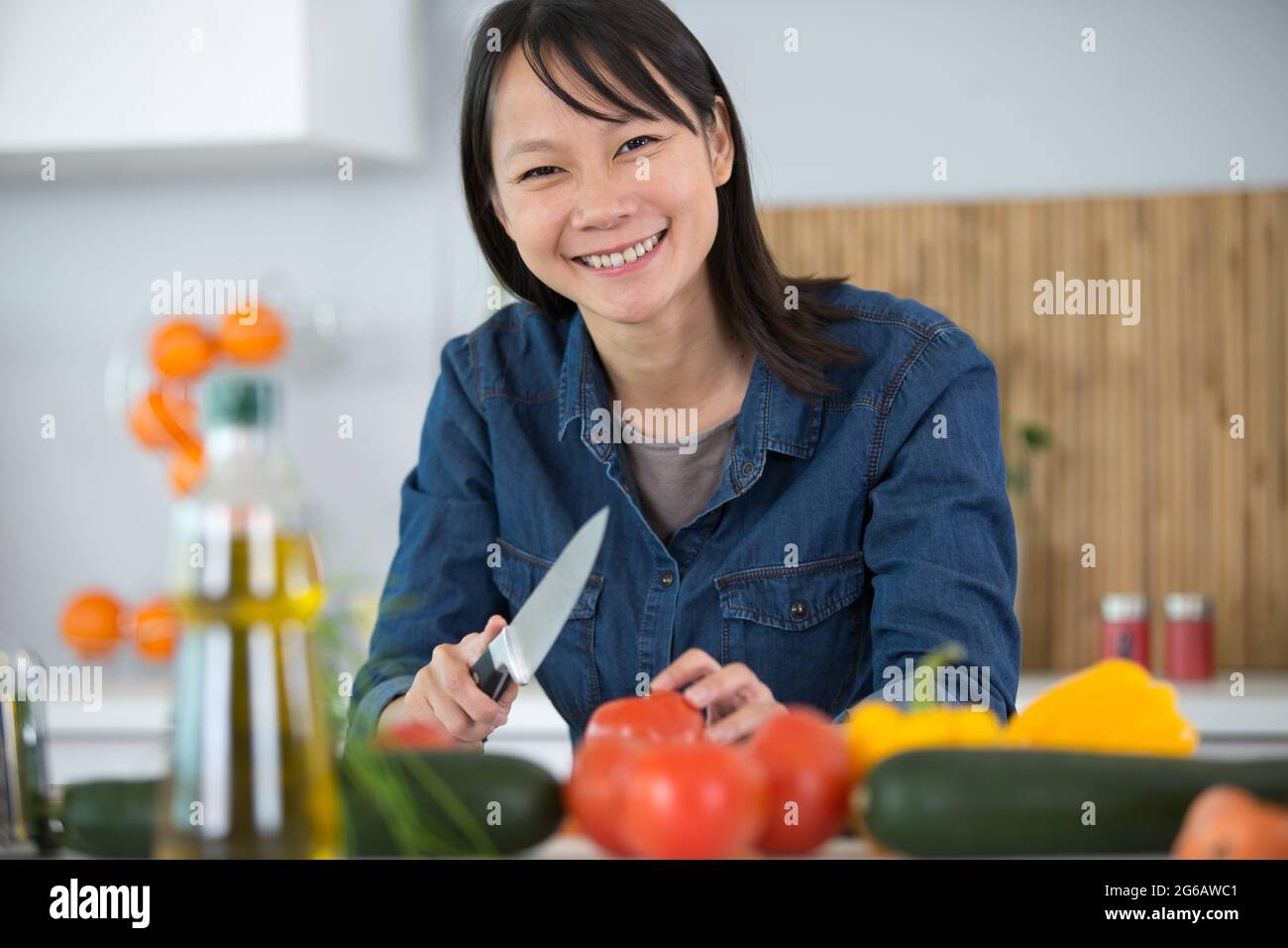 smiling asian woman cutting vegetables in domestic kitchen Stock Photo ...