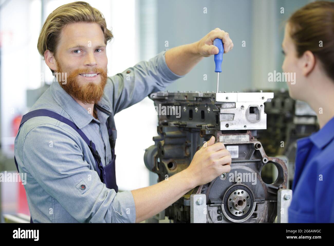 mechanic engineer inspecting engine with female apprentice Stock Photo ...