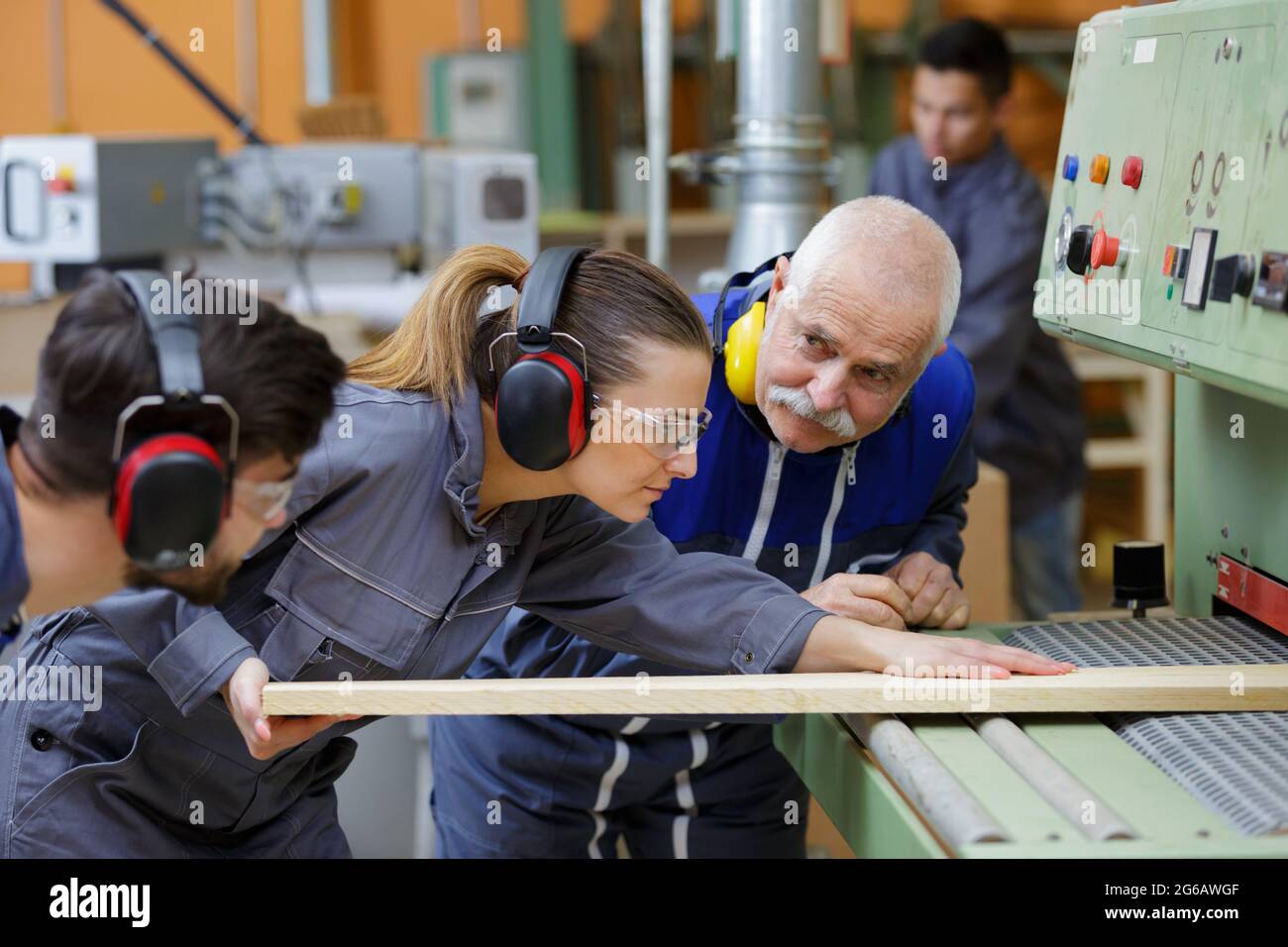 female apprentice passing wood through lathe Stock Photo - Alamy