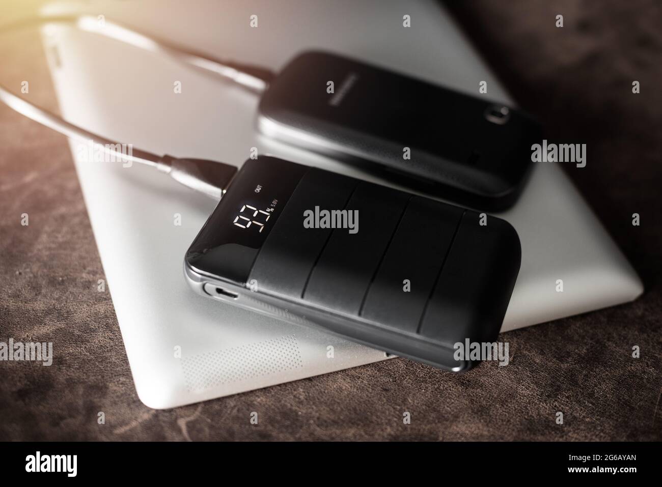Black power bank connected with USB cable. Charging smartphone with ...