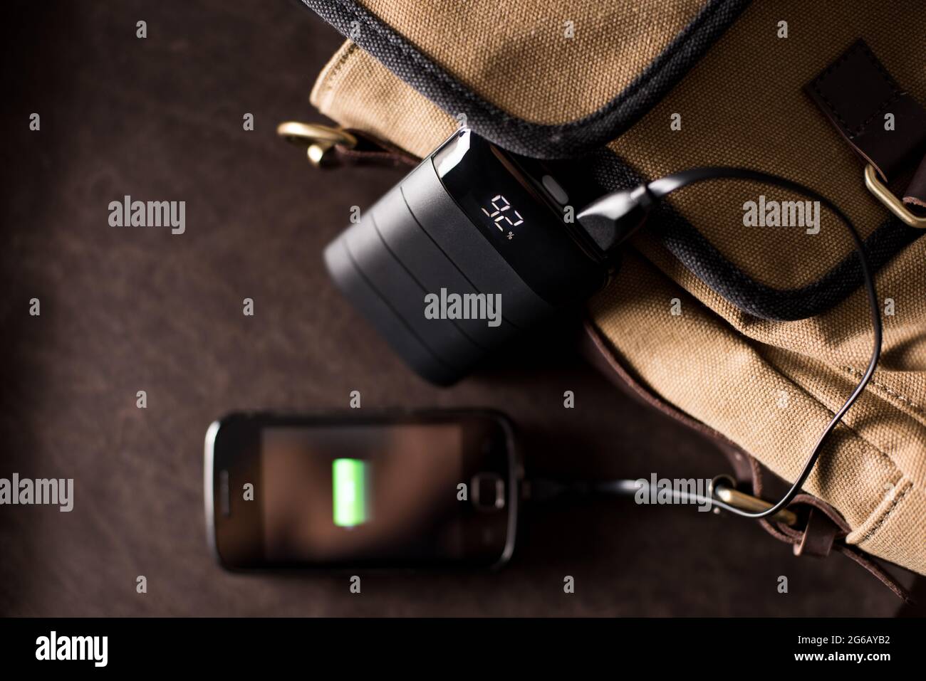 Black power bank connected with USB cable. Charging smartphone with ...