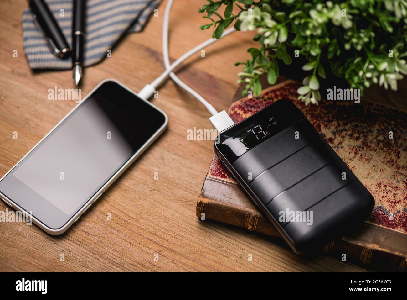 Black power bank connected with USB cable. Charging smartphone with ...