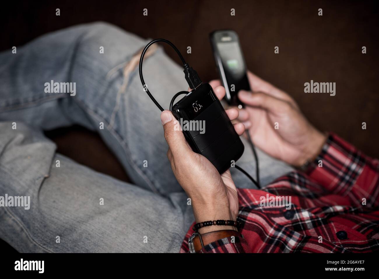 The man charging his smartphone with black power bank. Shallow depth of ...