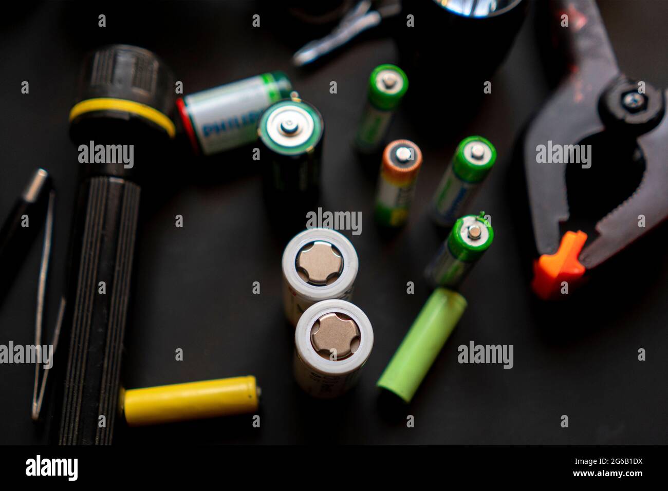 hands hold alkaline batteries above the black table with instruments ...