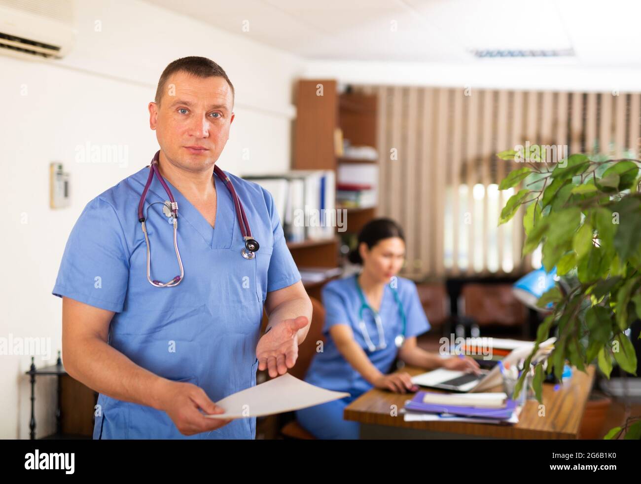 Professional doctor standing in office with patient medical history ...