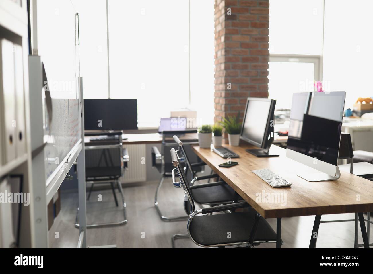 Computer monitors standing on table in empty office Stock Photo - Alamy