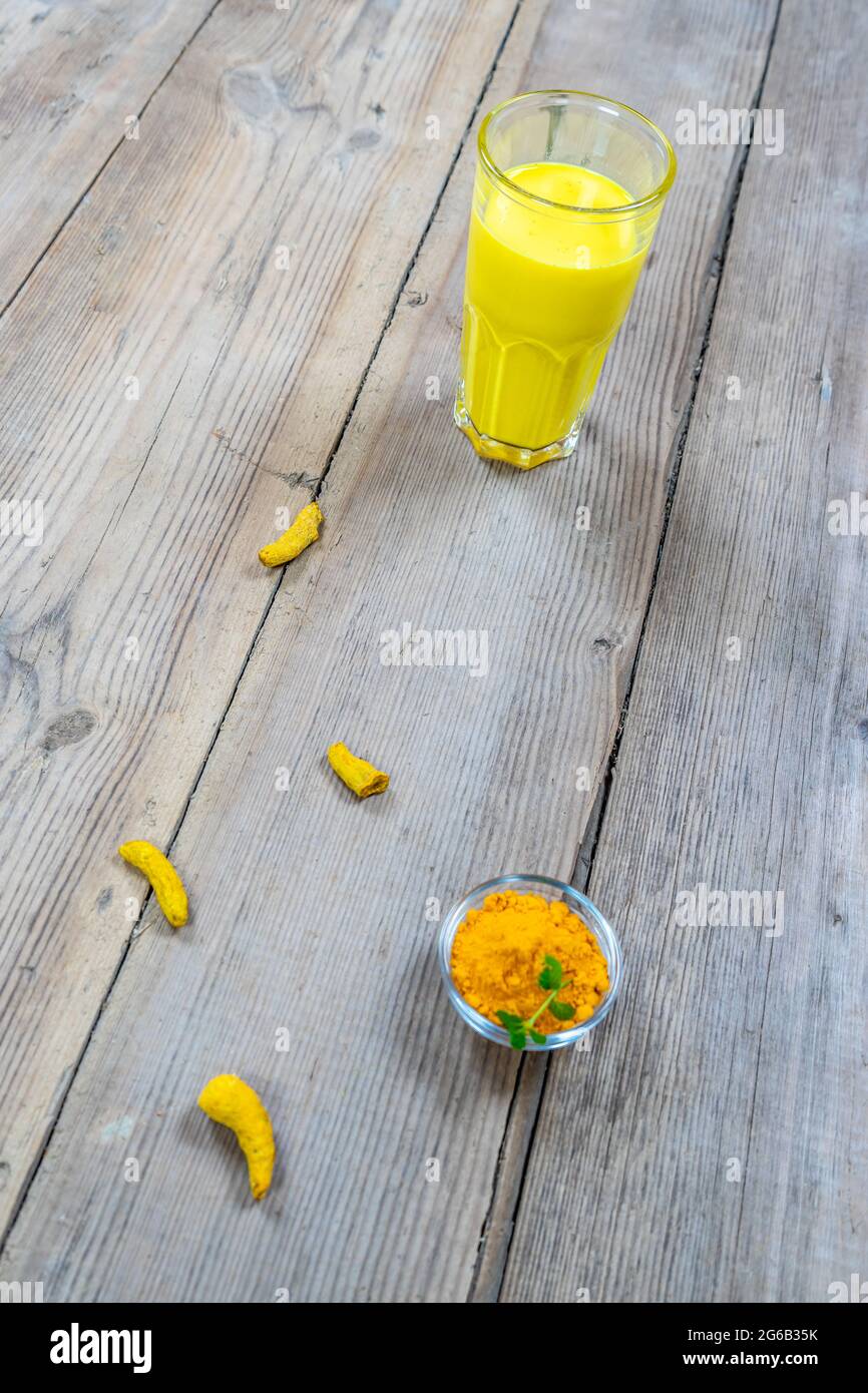 Golden milk in a glass cup on a wooden background Stock Photo - Alamy