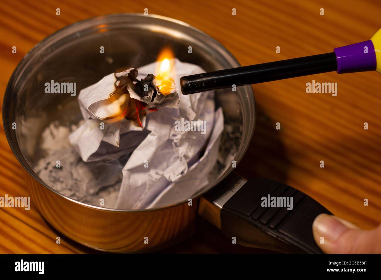 Lighter burning documents inside aluminum pot. Letters on fire ...