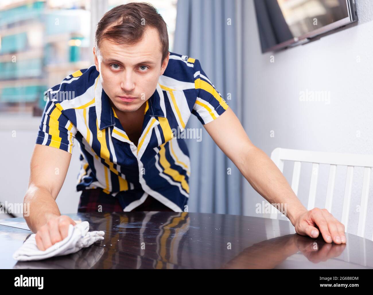 Man is cleaning dust from the desk in the liveroom Stock Photo - Alamy