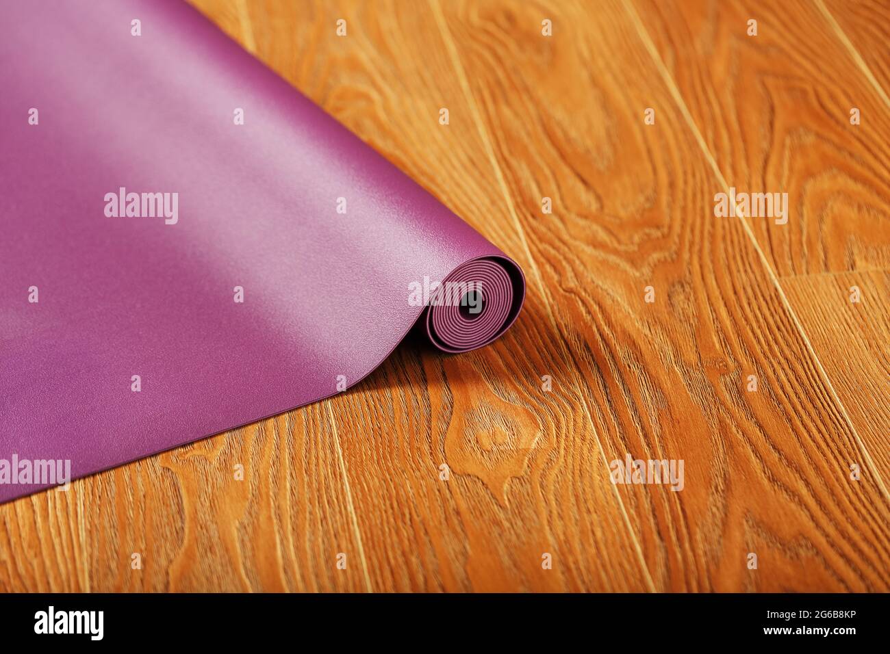 An unfolded lilac-colored yoga mat is unfolded on the wooden floor. Top ...
