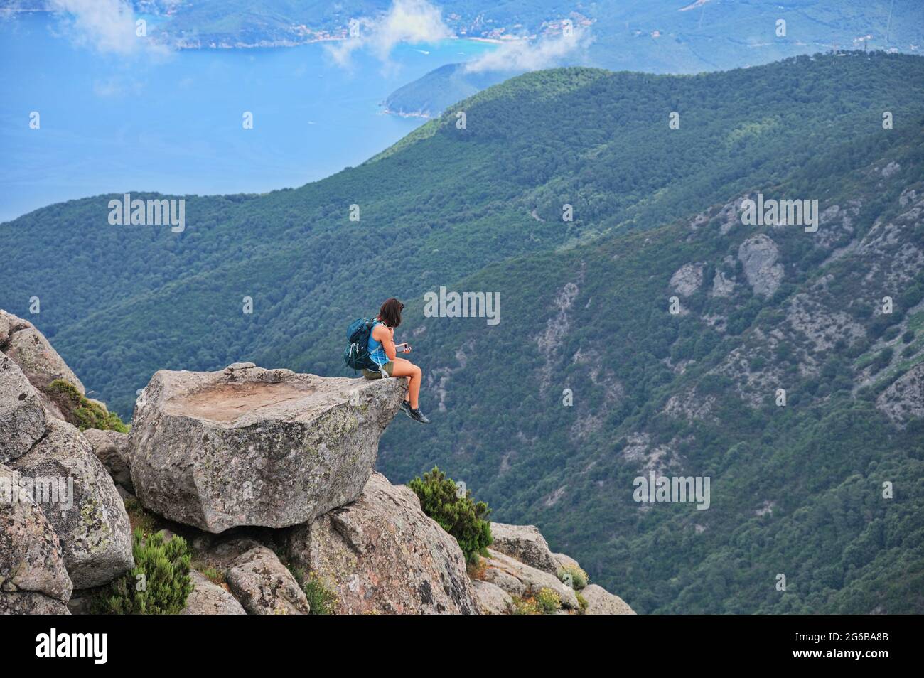 Young woman sitting on a rock above the abyss Stock Photo - Alamy