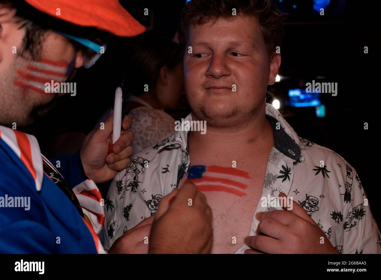 An Israeli man dressed in an Uncle Sam outfit paints the American flag ...