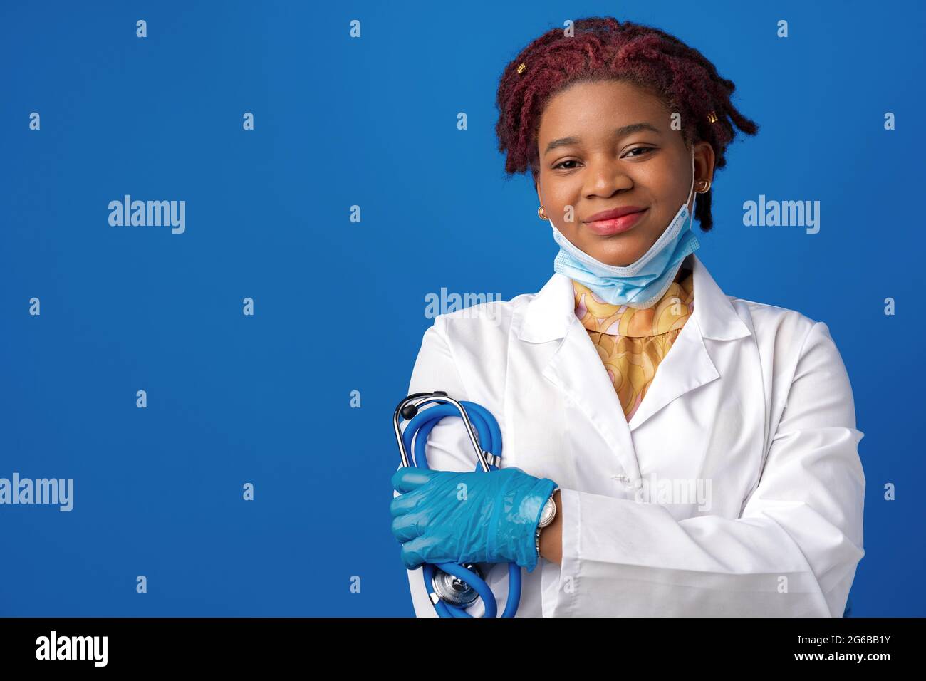 Portrait of african female doctor in lab coat with face mask and ...