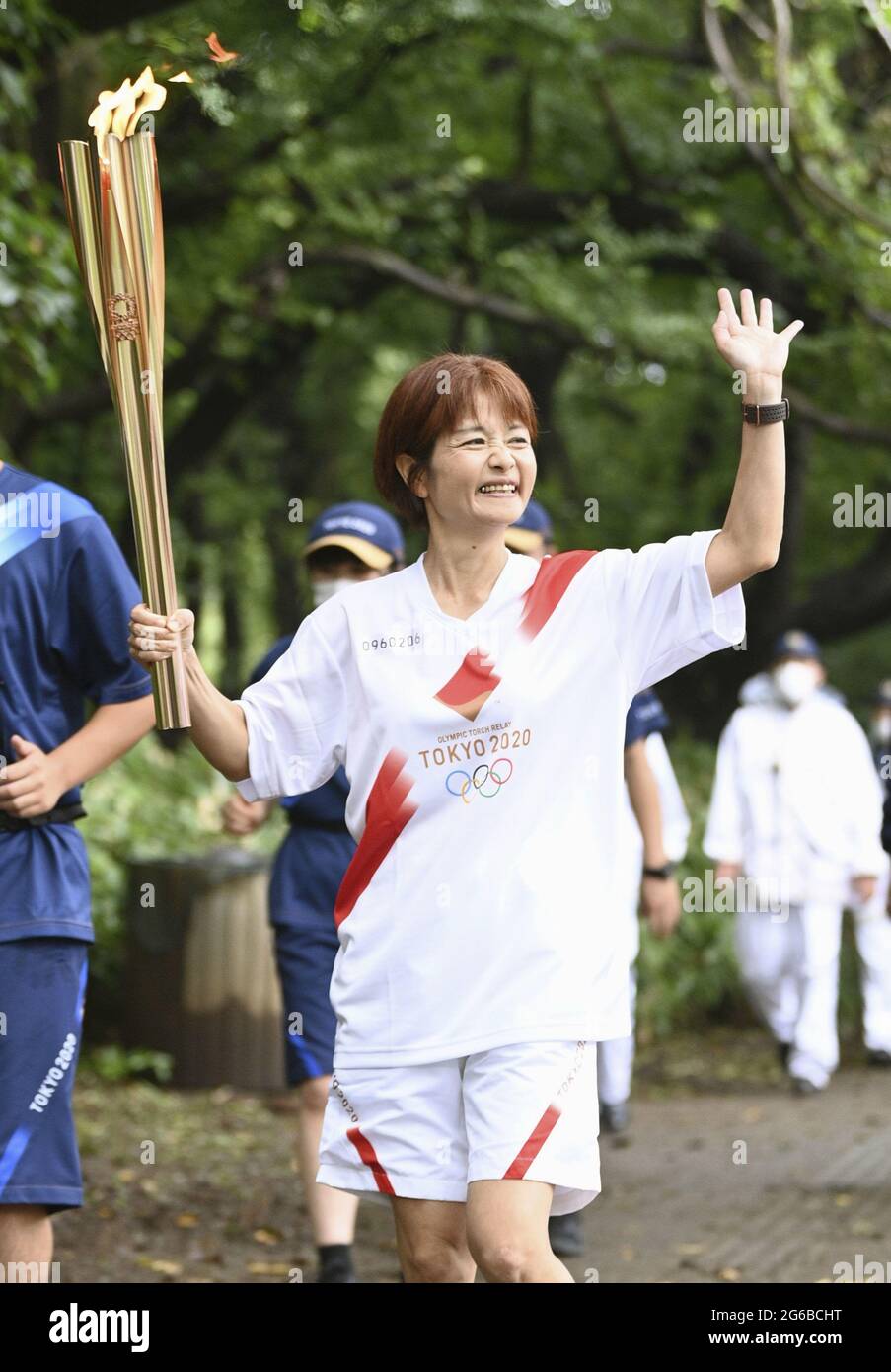 A Tokyo Olympic torch relay runner waves during the torch relay in the ...