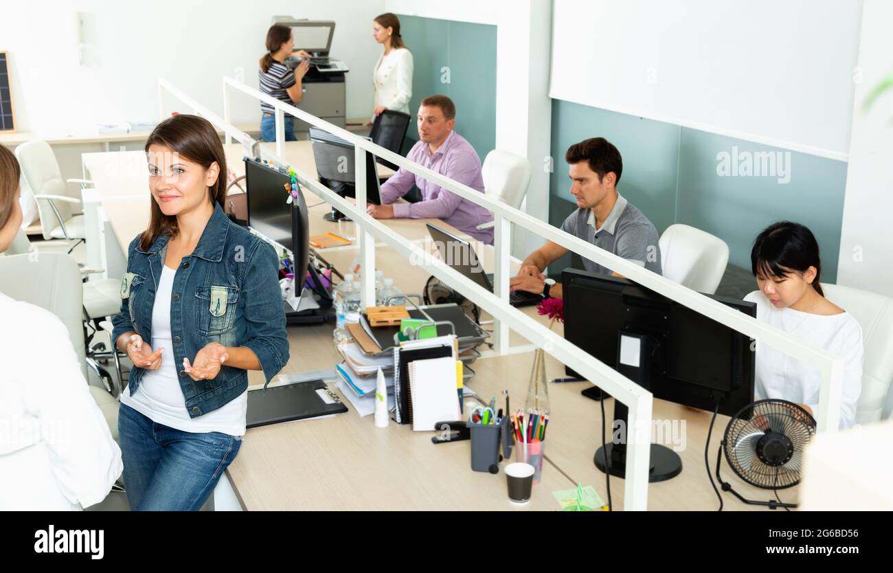 Male and female office co-workers having conversation at desk in office ...