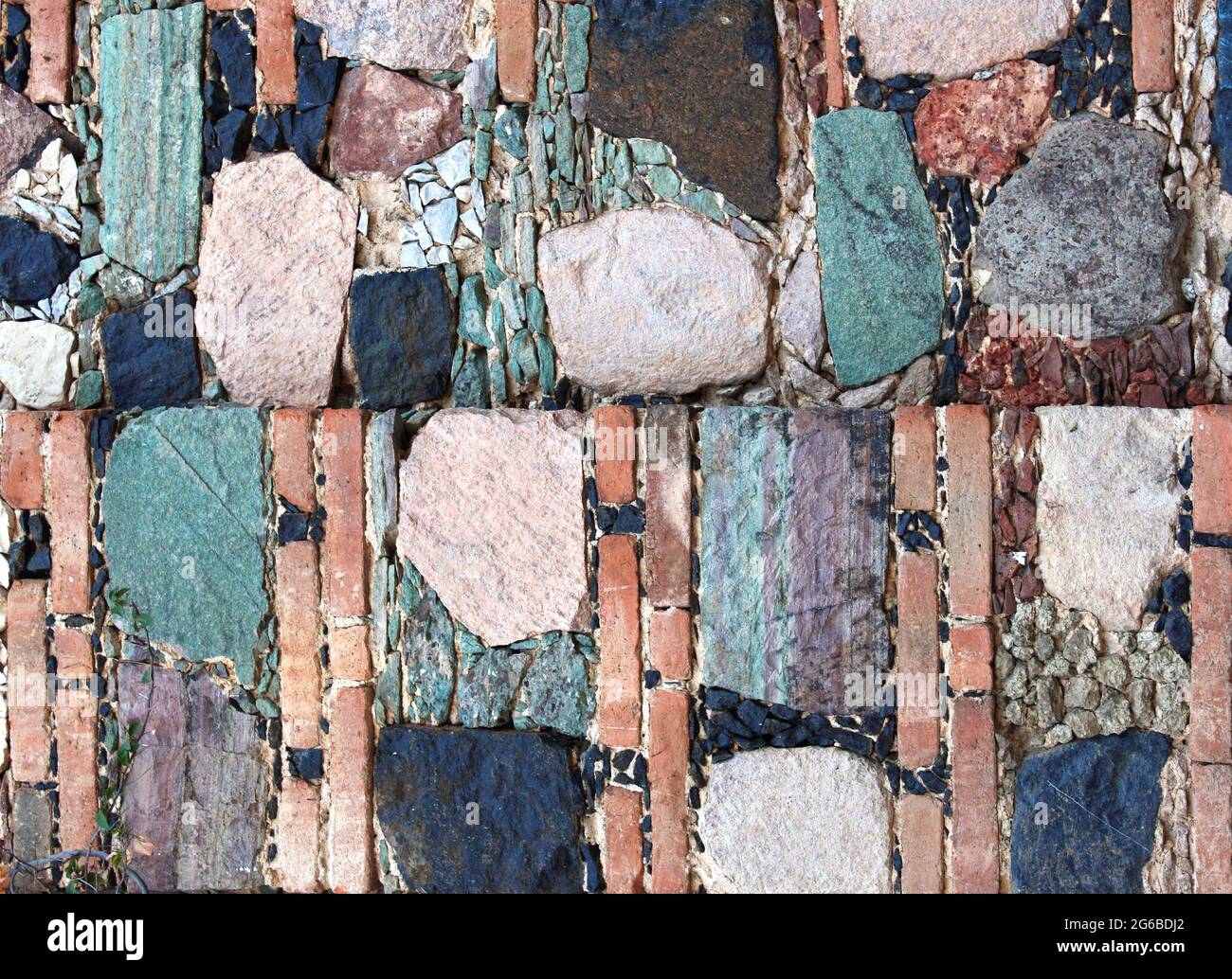 Texture of wall with stone blocks of red, yellow, green and gray colors ...