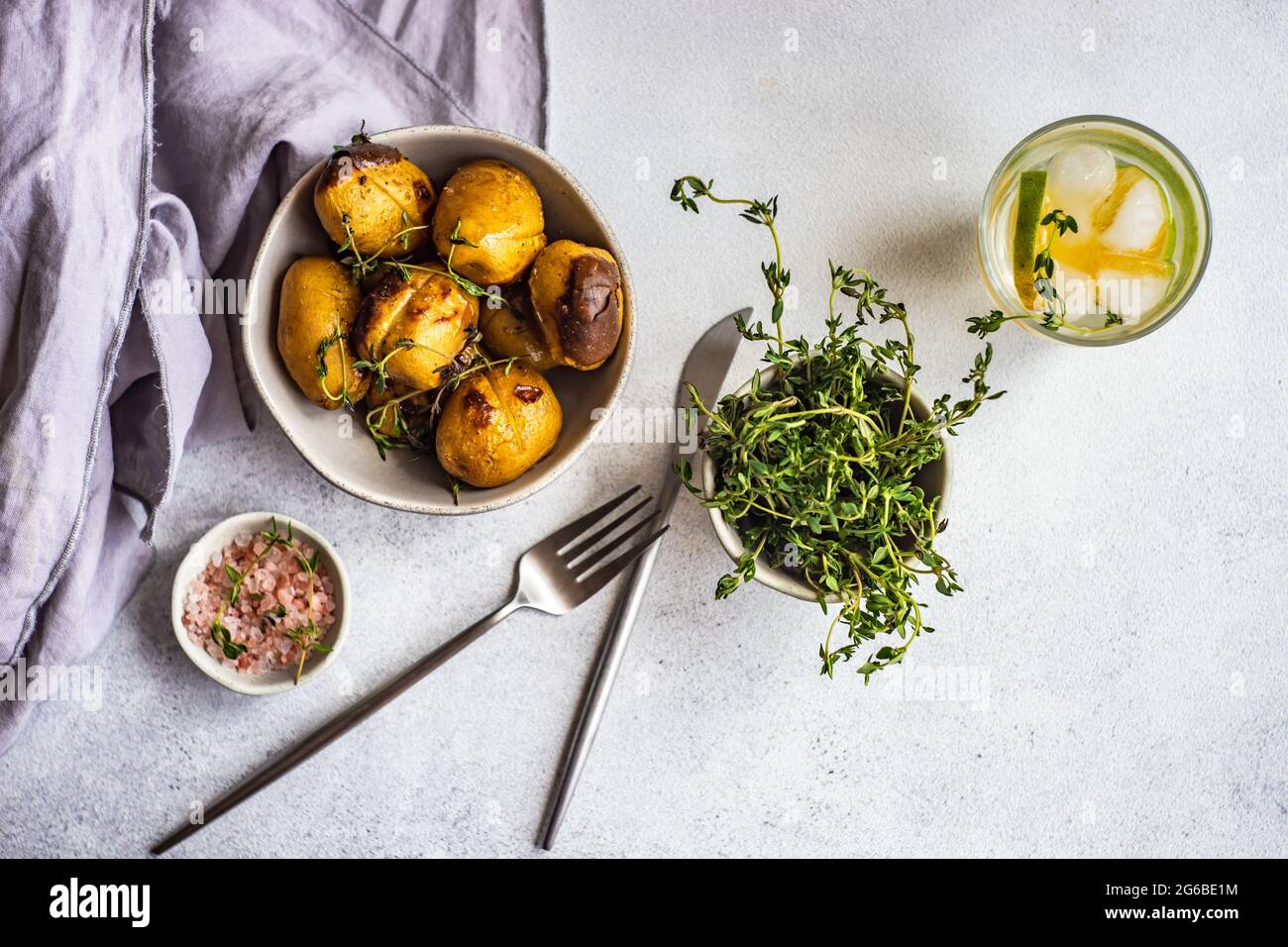 Overhead view of a bowl of roasted potatoes on a table with a glass of ...