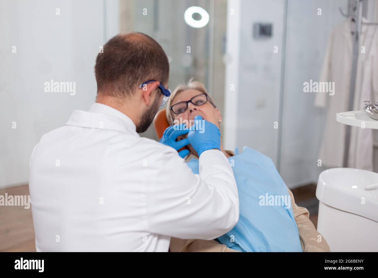 Denstis in cabinet repairing senior patient tooth in dental clinic ...